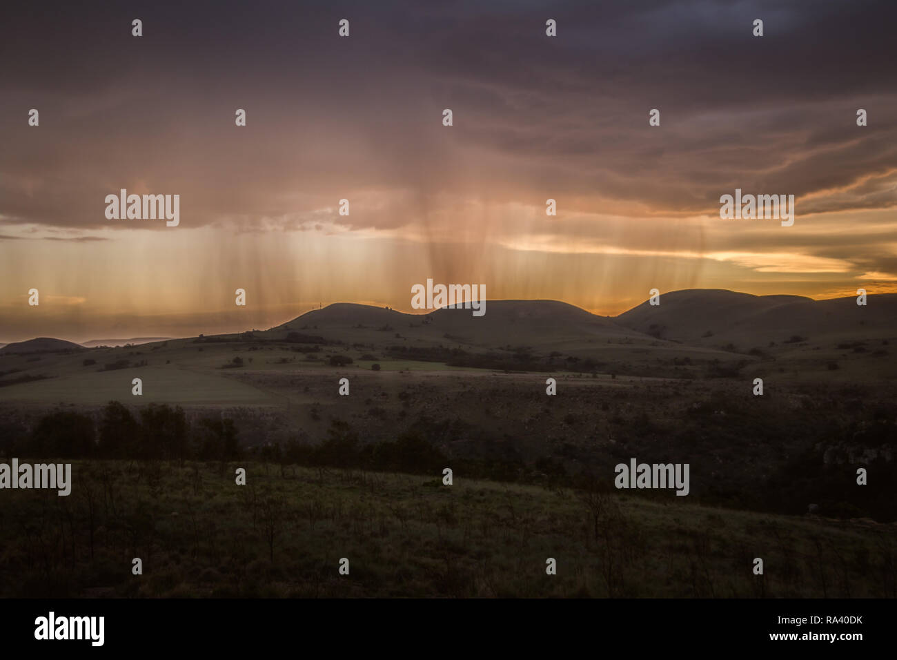 Rain falling on a distant mountain with orange sunset Stock Photo - Alamy