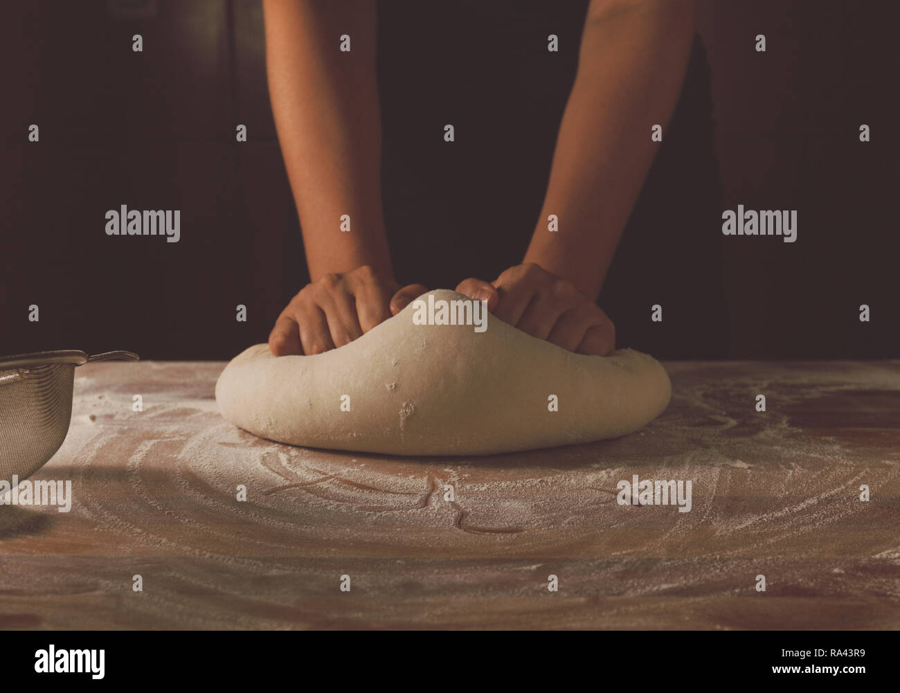 Making dough by female hands on a wooden baking table. Dark black ...