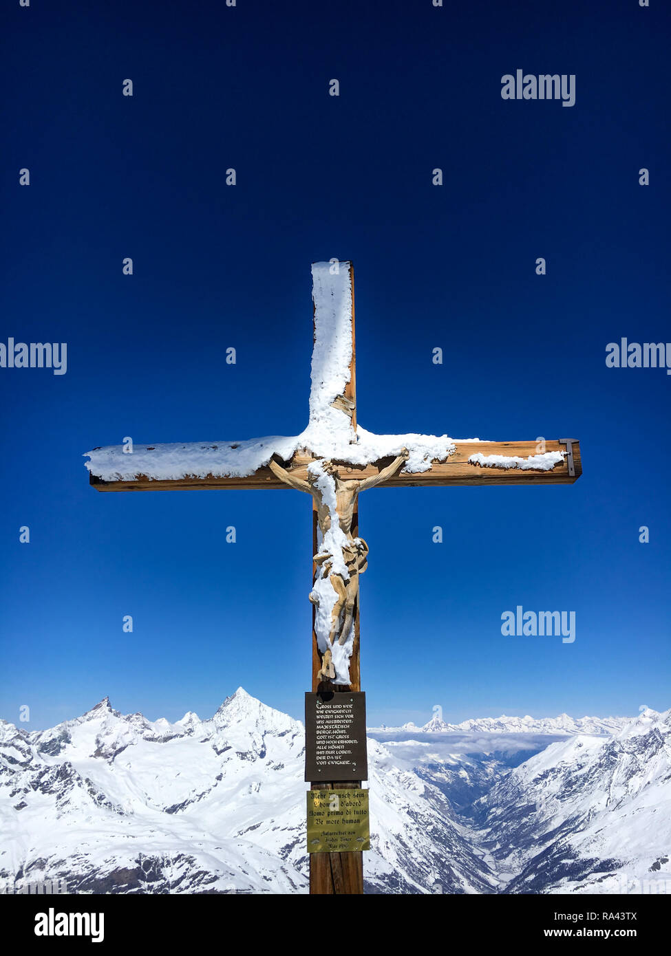 Snow covered cross with a wooden figure of Jesus Christ at peak of ...