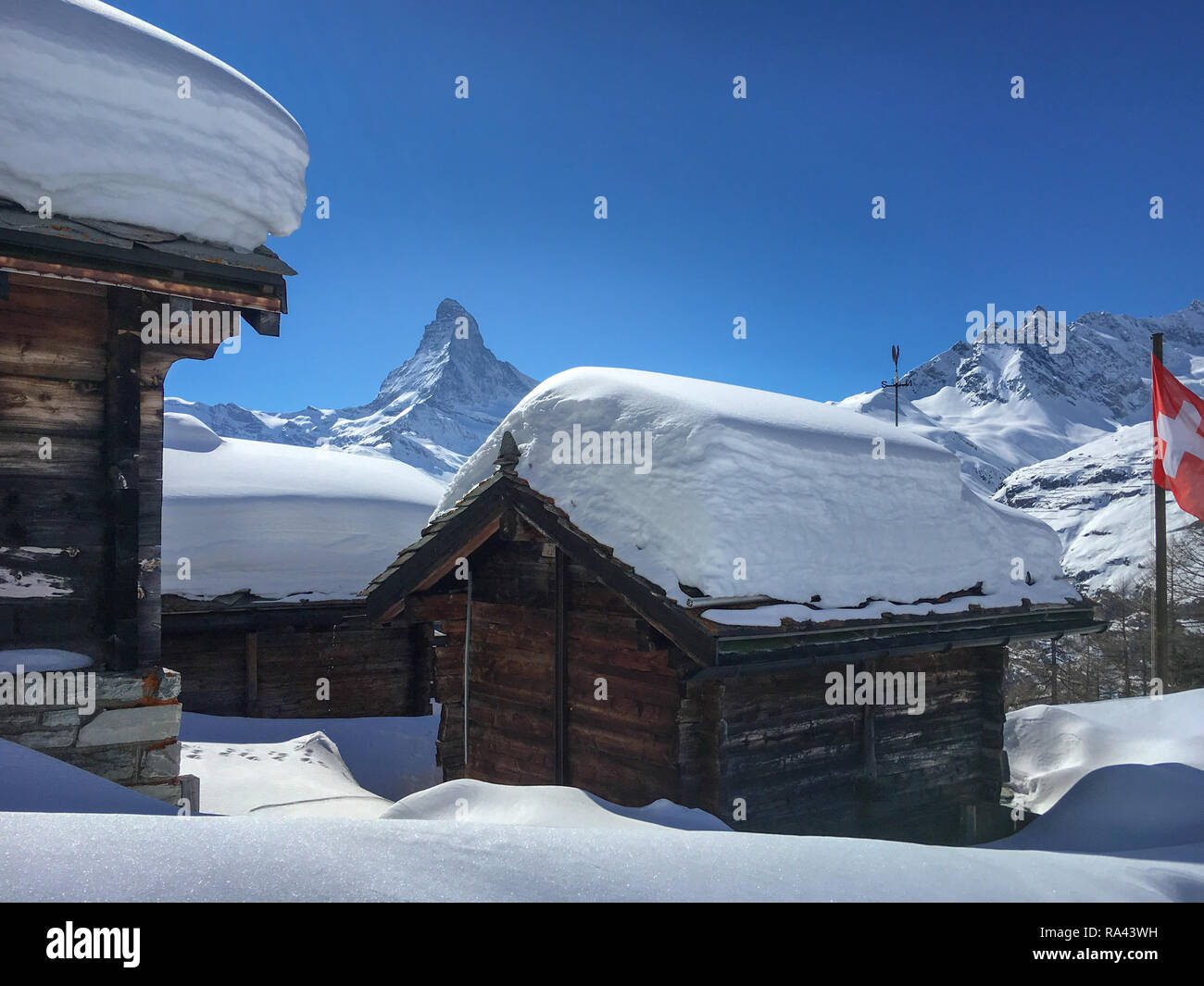 Cottages with lots of snow on the rooftop and Swiss flag in front of ...