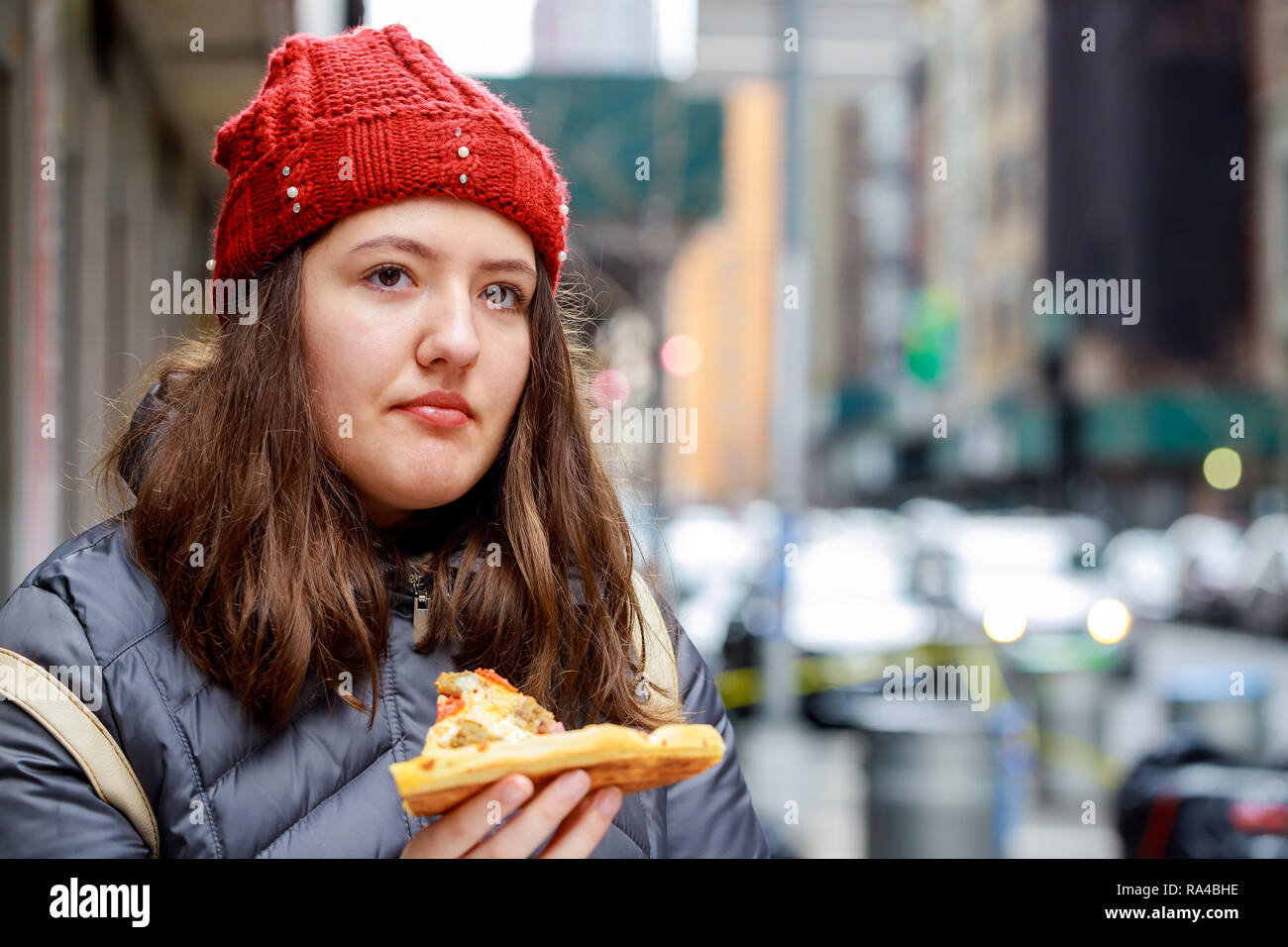Young pretty girl teenager eating pizza in a pizza at restaurant street ...