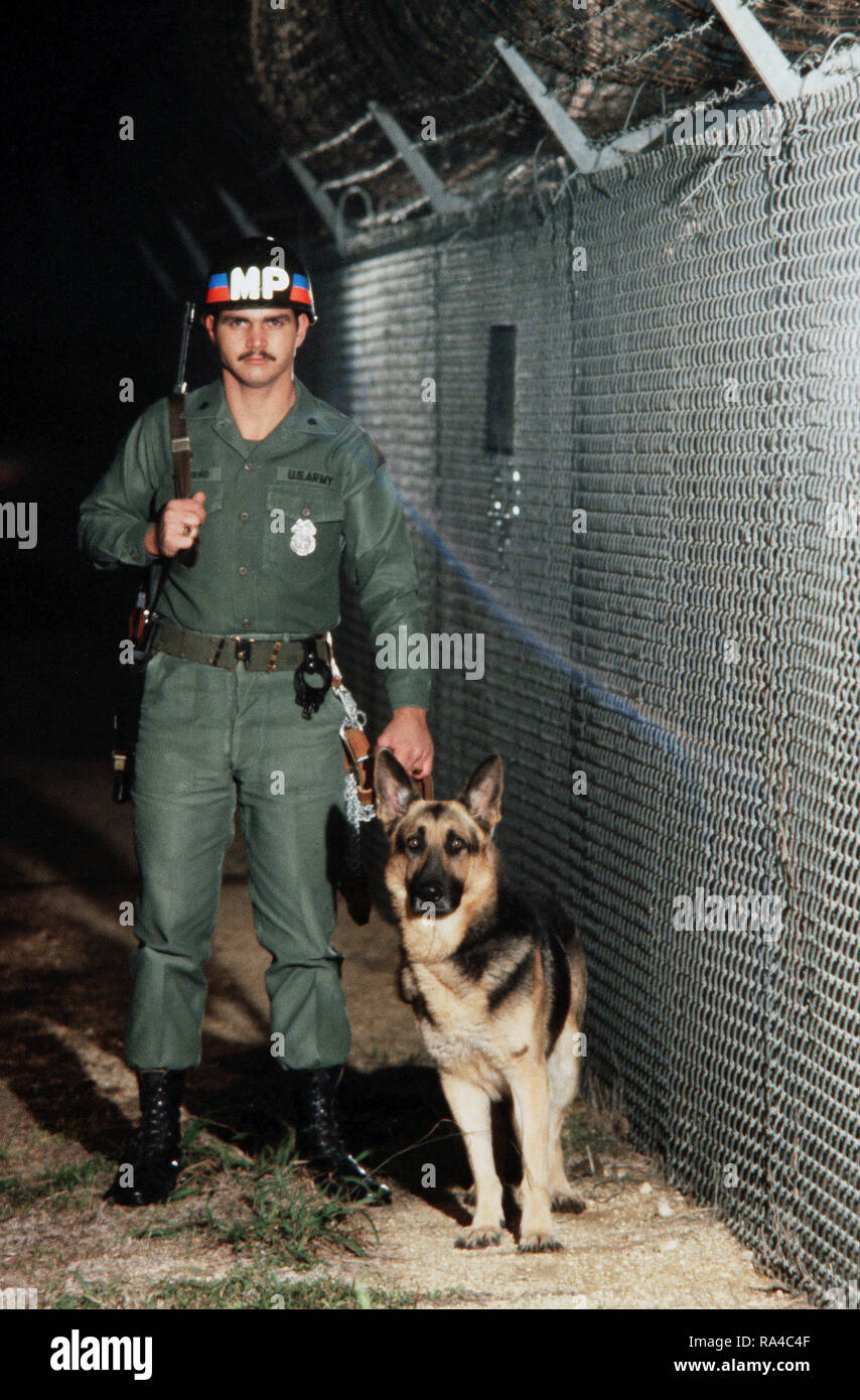1978 - A US Army military policeman patrols a fence line with a patrol ...