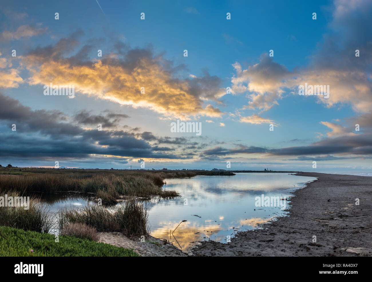 Glowing clouds of dawn mimiced in smooth and reflective surface of pond ...