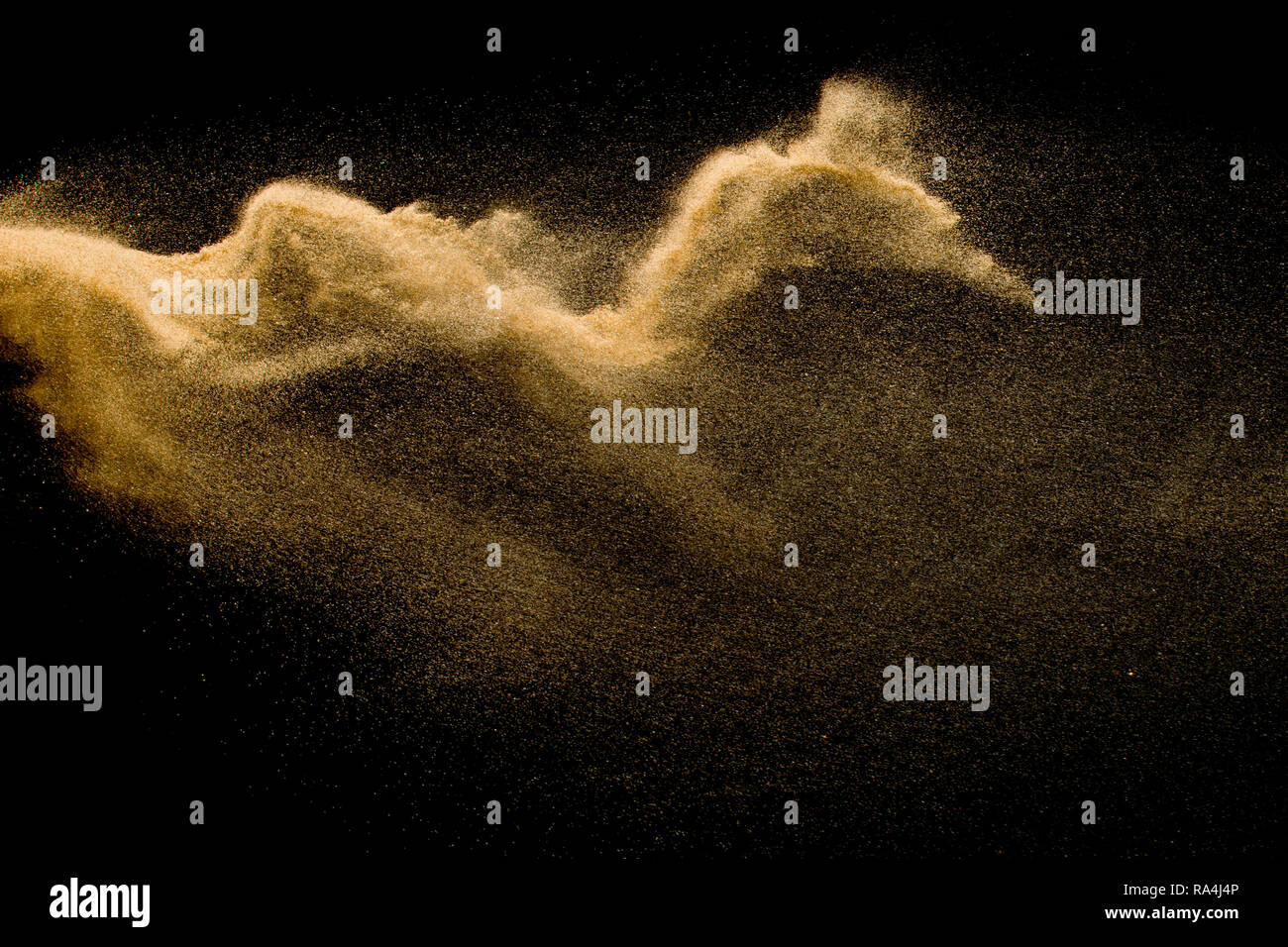 Abstract sand cloud. Golden colored sand splash agianst dark background ...