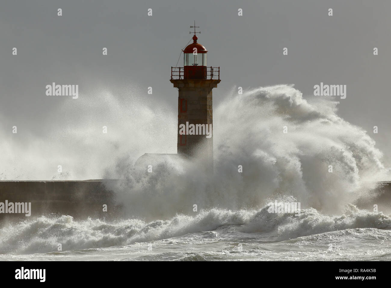 Stormy waves over lighthouse and pier with interesting autumn light ...