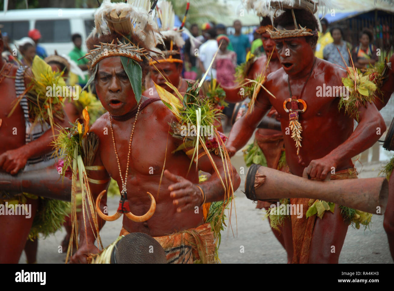 Colourfully dressed and face painted men and women dancing as part of a ...