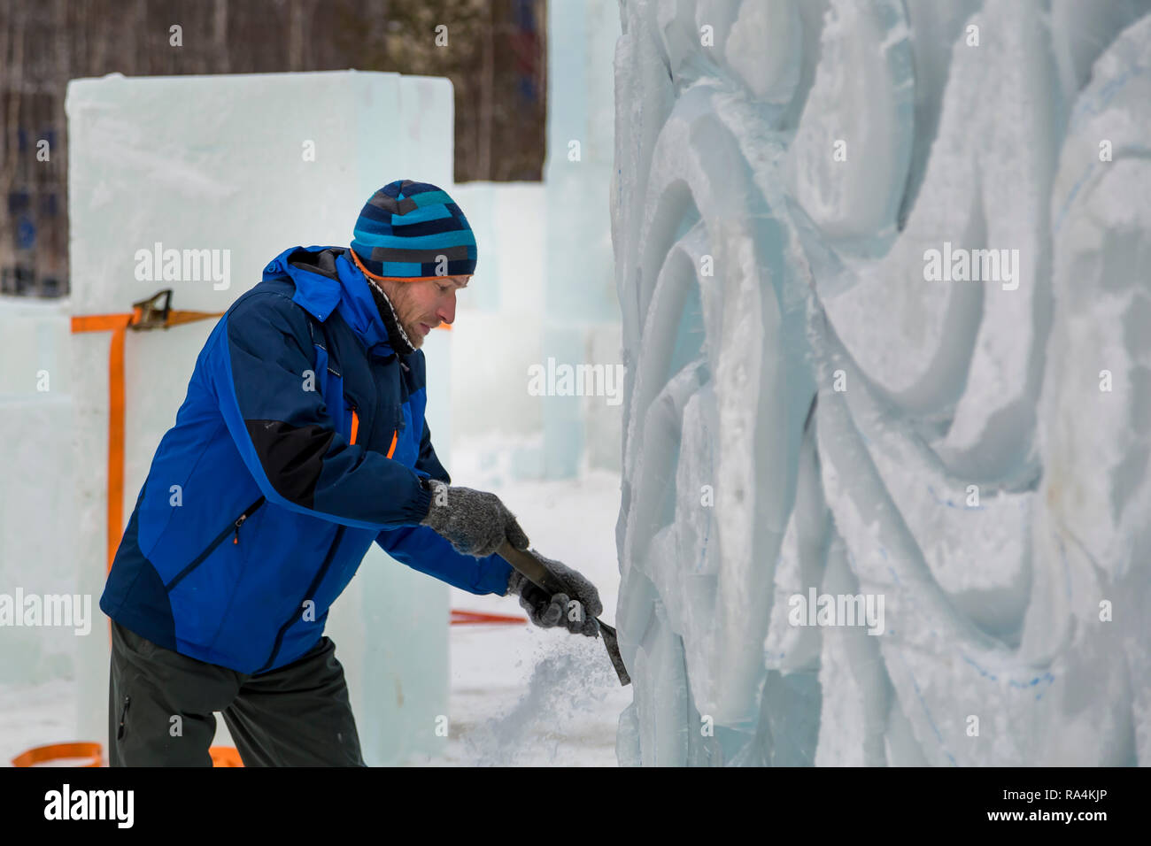 The sculptor cuts an ice figure for Christmas from a block of ice with ...
