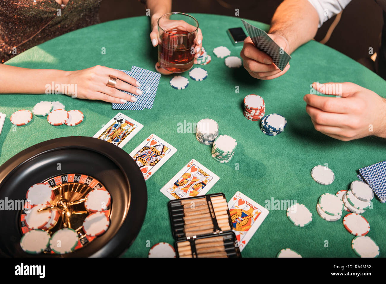 cropped image of girl and croupier playing poker at table in casino ...