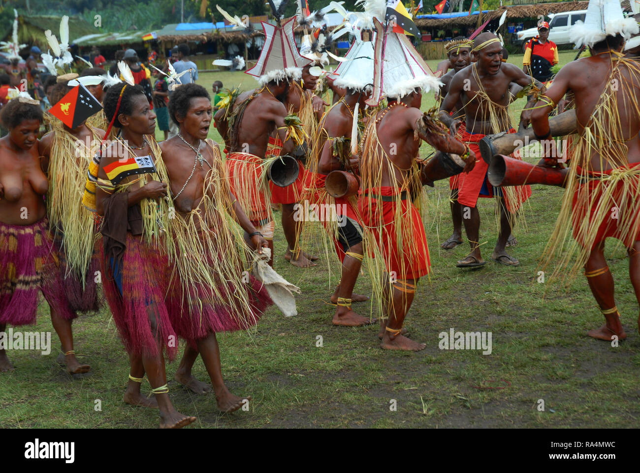 Colourfully dressed and face painted men and women dancing as part of a ...