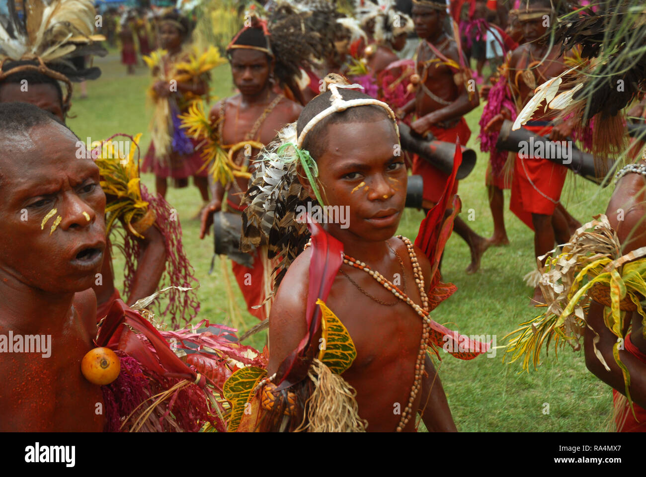 Colourfully dressed and face painted men and women dancing as part of a ...
