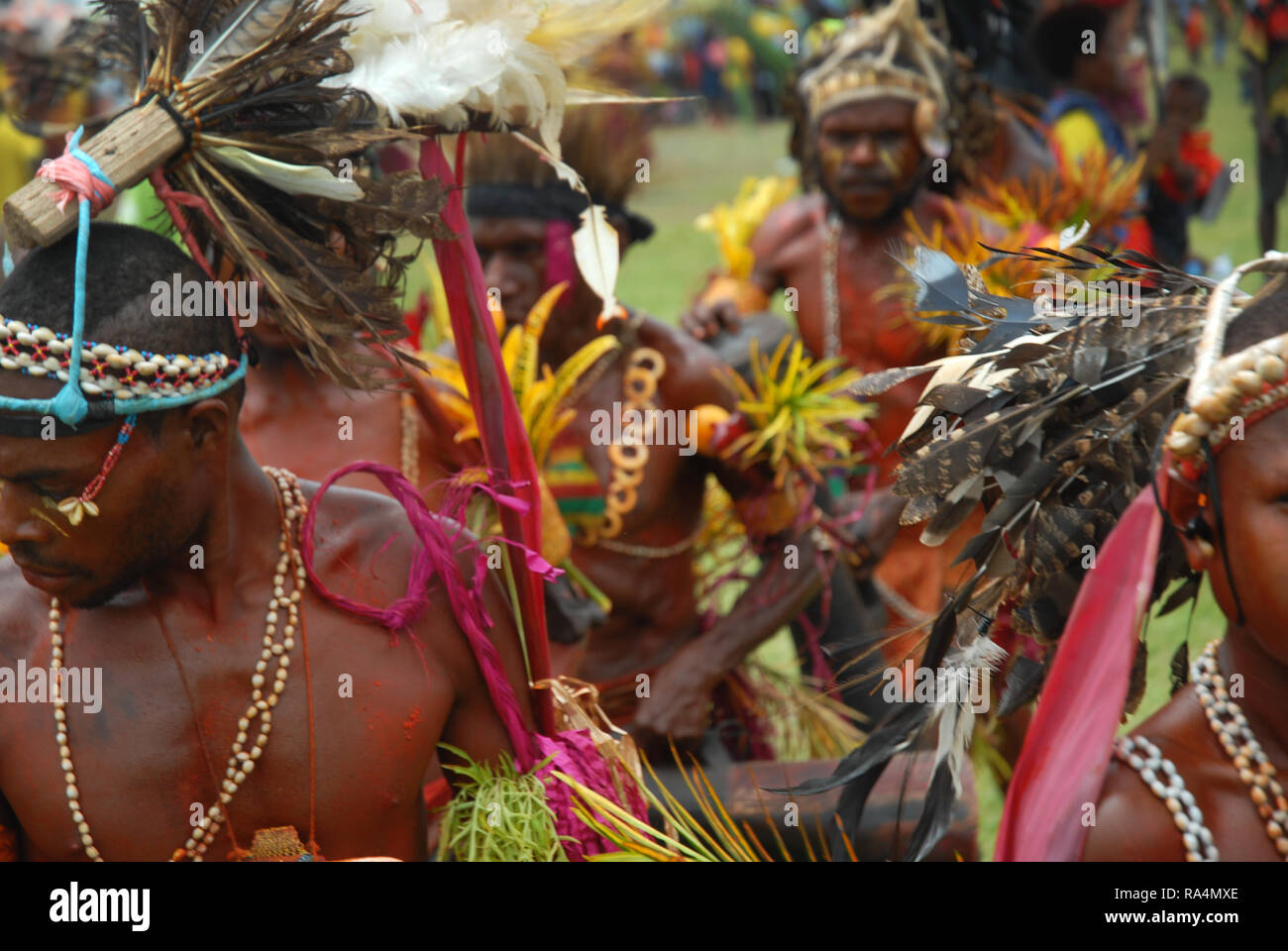 Colourfully dressed and face painted men and women dancing as part of a ...