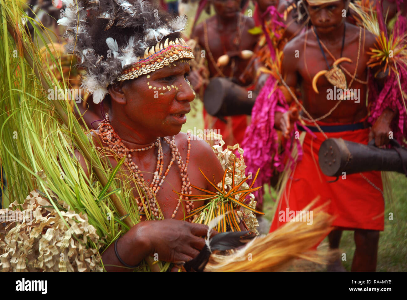 Colourfully dressed and face painted men and women dancing as part of a ...