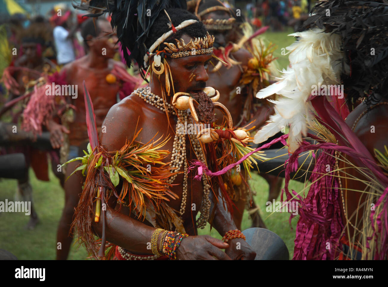 Colourfully dressed and face painted men and women dancing as part of a ...