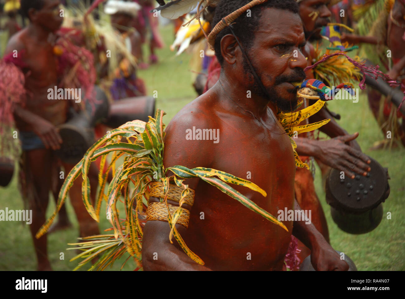 Colourfully dressed and face painted men and women dancing as part of a ...