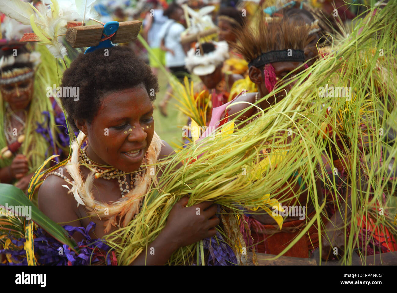 Colourfully dressed and face painted men and women dancing as part of a ...