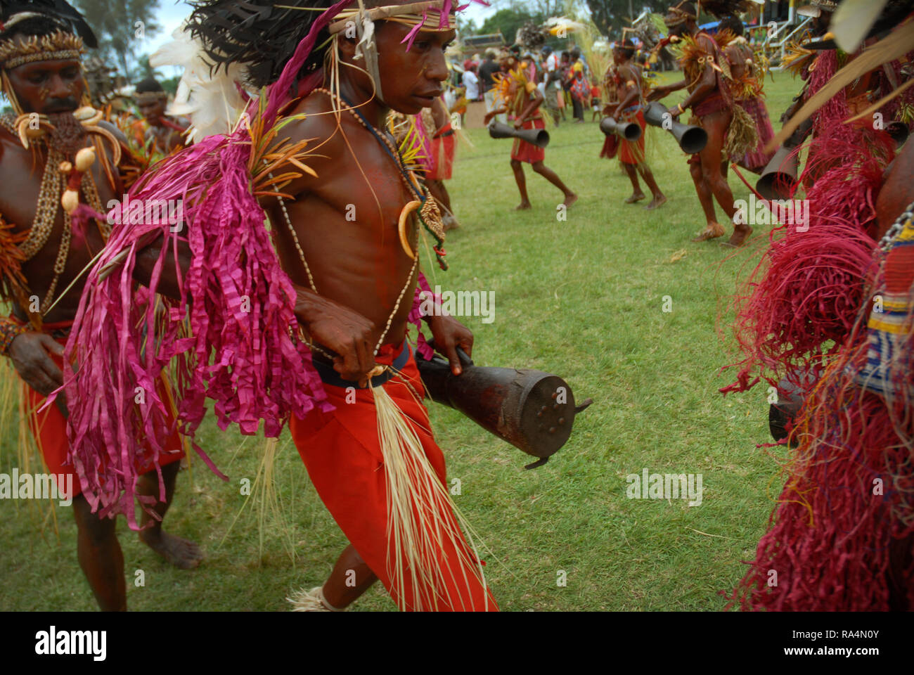 Colourfully dressed and face painted men and women dancing as part of a ...