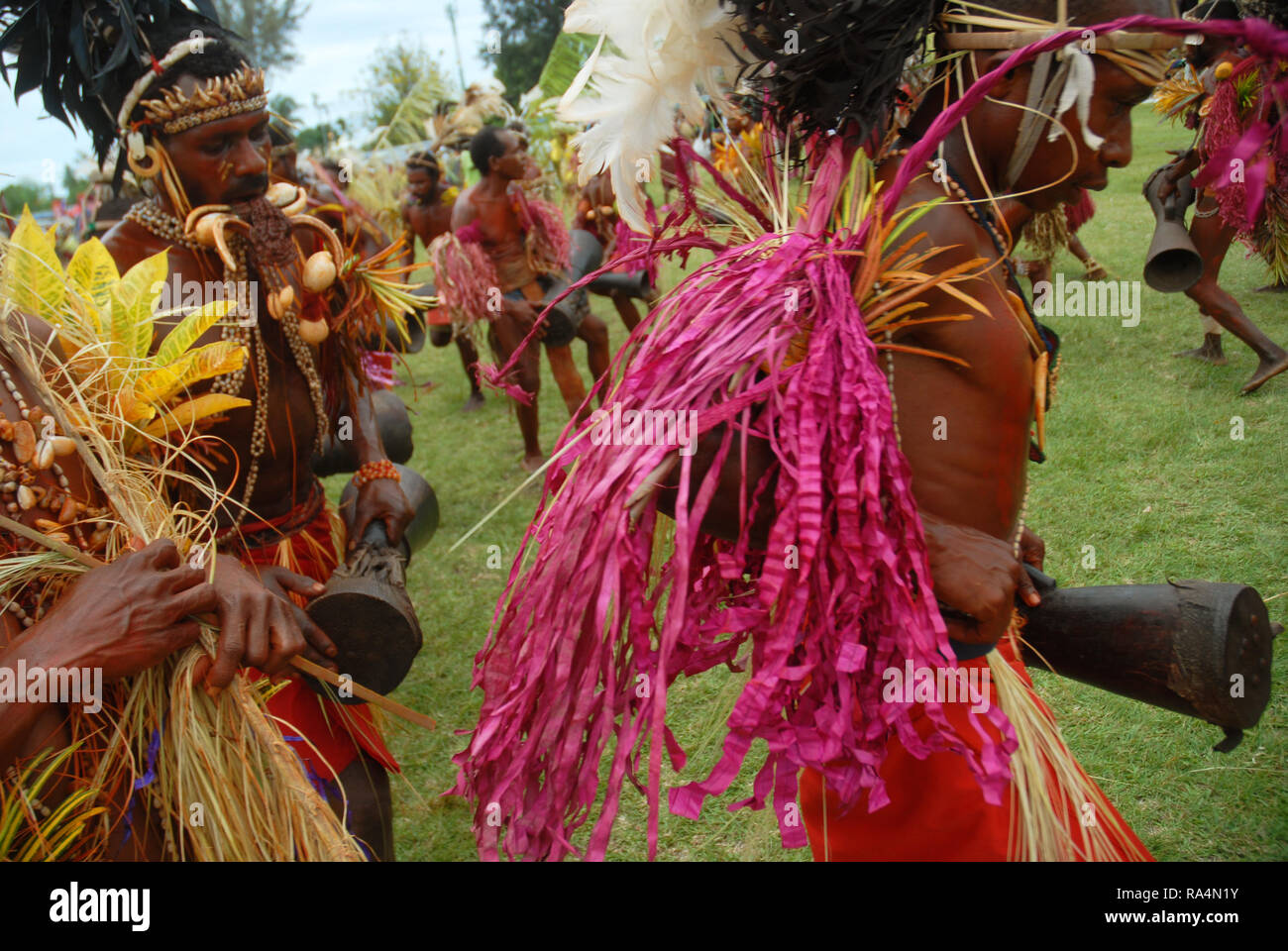Colourfully dressed and face painted men and women dancing as part of a ...