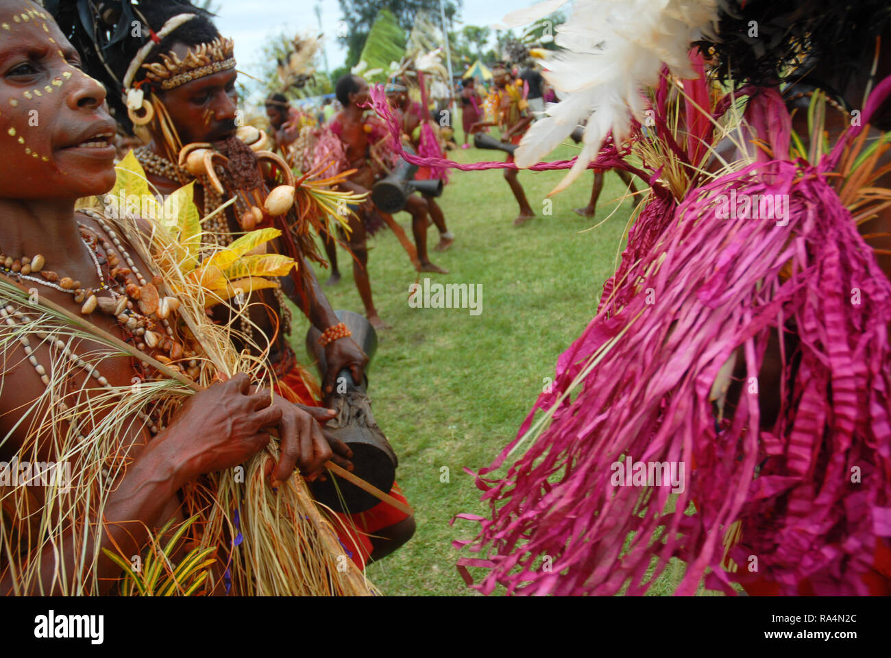 Colourfully dressed and face painted men and women dancing as part of a ...