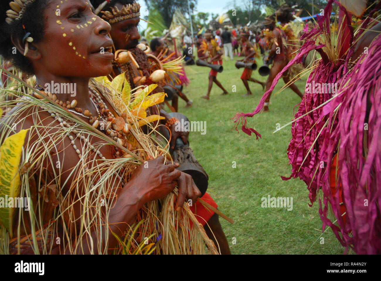 Colourfully dressed and face painted men and women dancing as part of a ...