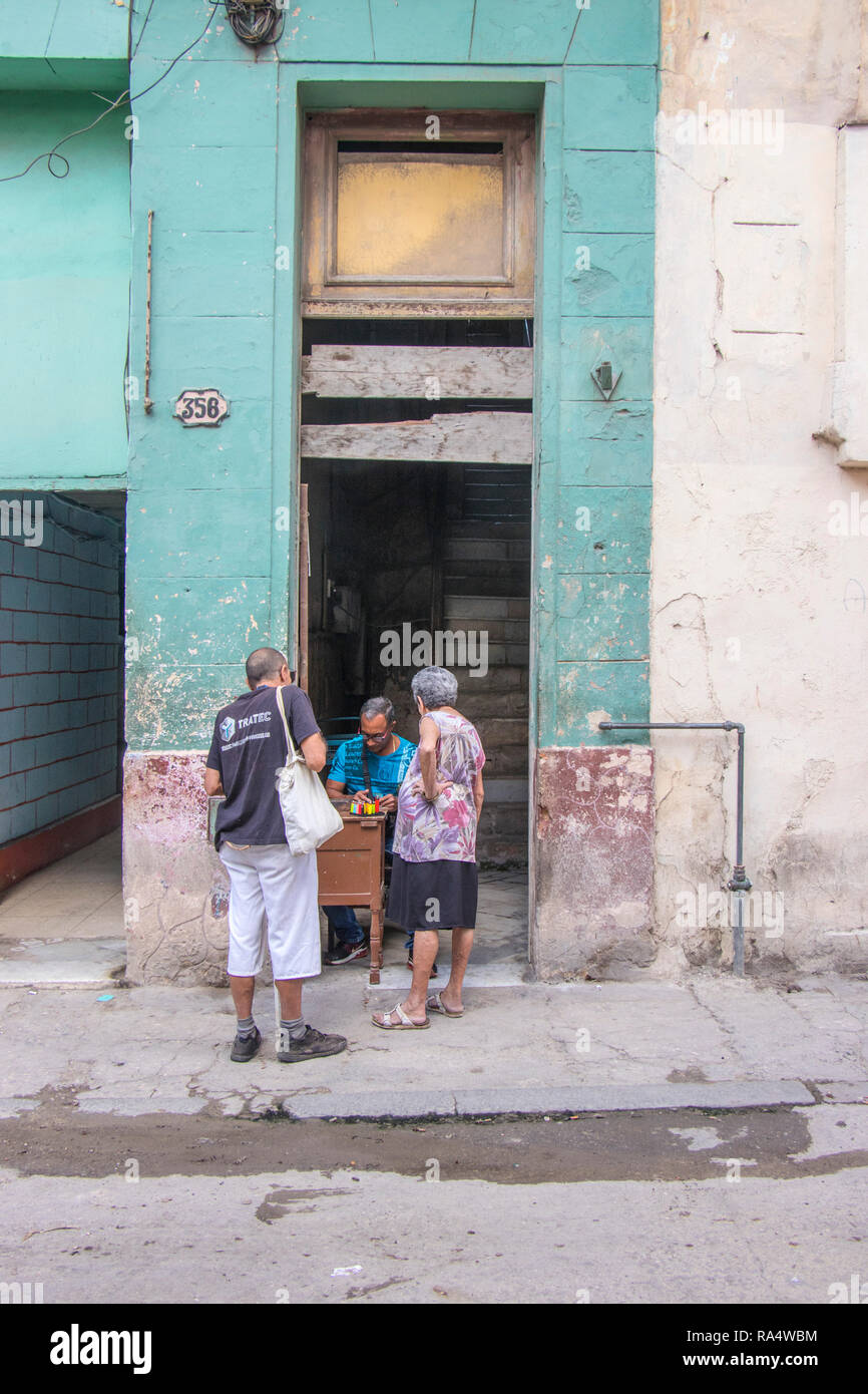 man and woman buy good from small open air store in a havana street ...