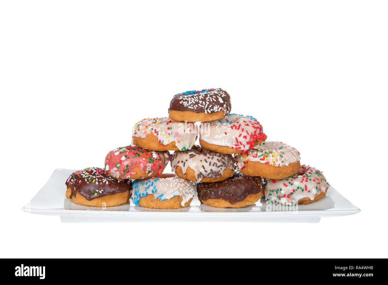 Rectangular plate with frosted cake donuts stacked, covered with candy ...