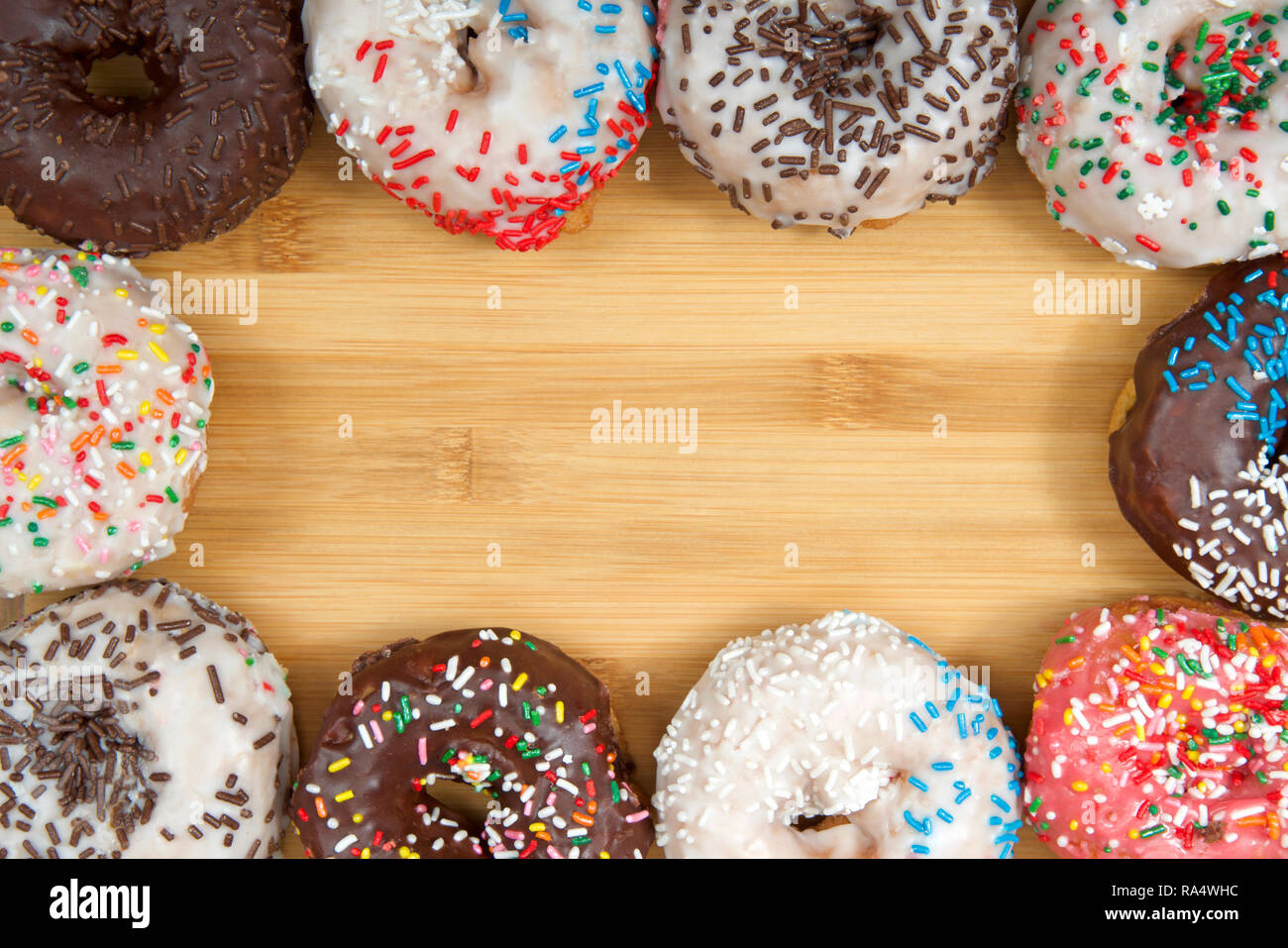 Flat lay view of many Frosted donuts with candy sprinkles arranged in a ...