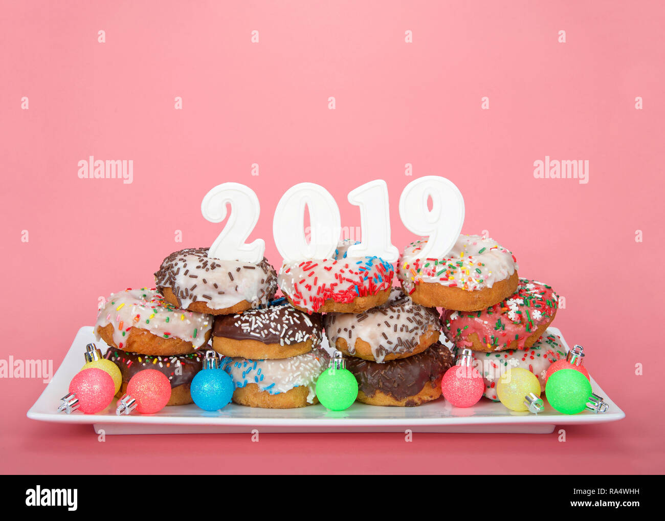 Rectangular plate with frosted cake donuts stacked, covered with candy ...