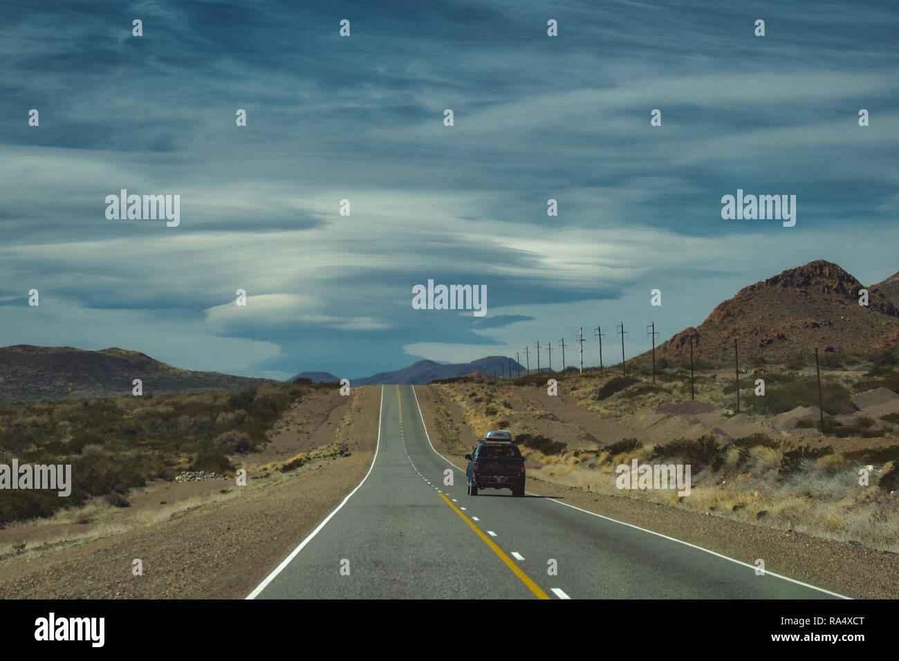 4x4 vehicle driving along a desert road on a cloudy day in a ...