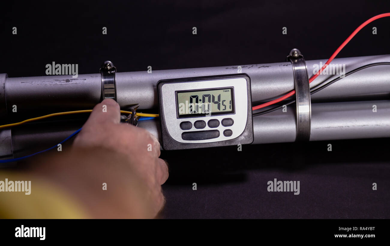 Hand cutting wire on pipe bomb with an lcd clock timer to trigger ...