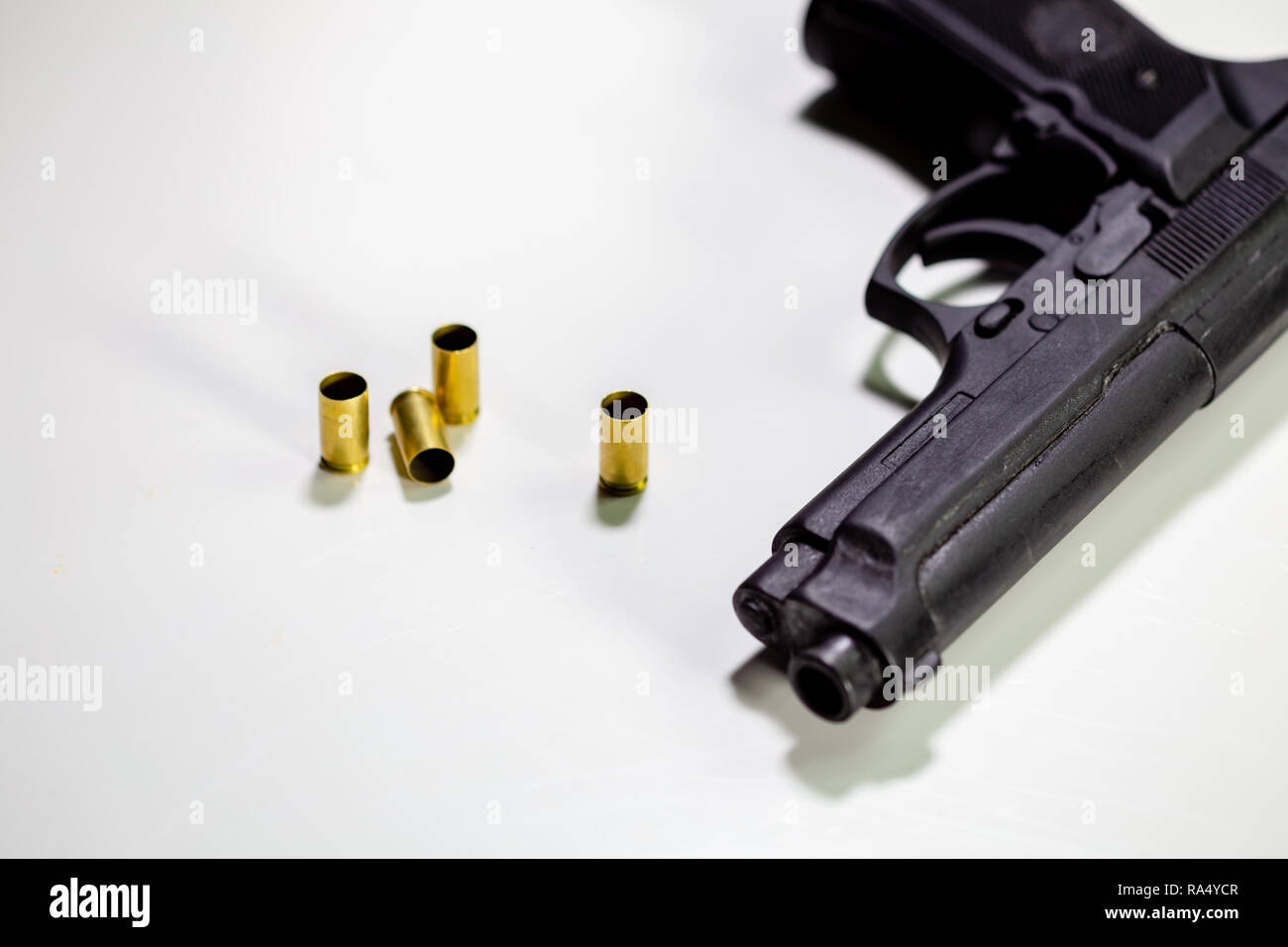 Pistol with 9mm shell casings on white table Stock Photo - Alamy