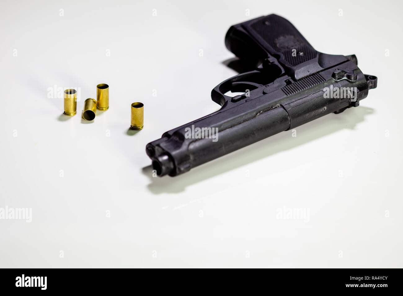 Pistol with 9mm shell casings on white table Stock Photo - Alamy