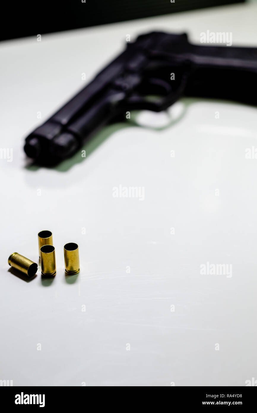 Pistol with 9mm shell casings on white table Stock Photo - Alamy