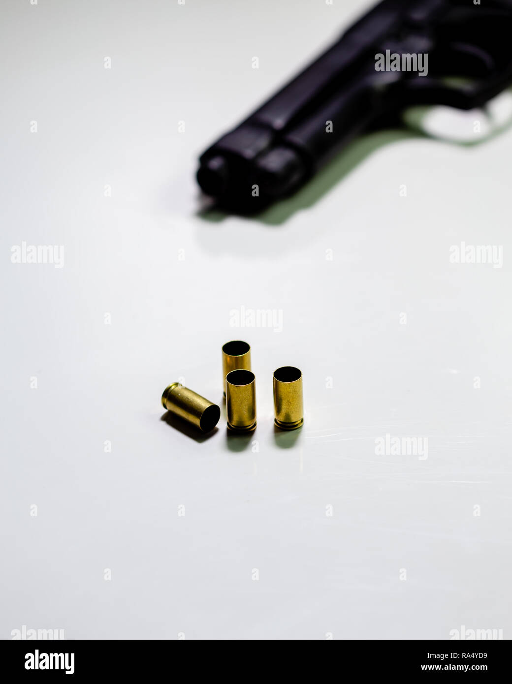 Pistol with 9mm shell casings on white table Stock Photo - Alamy