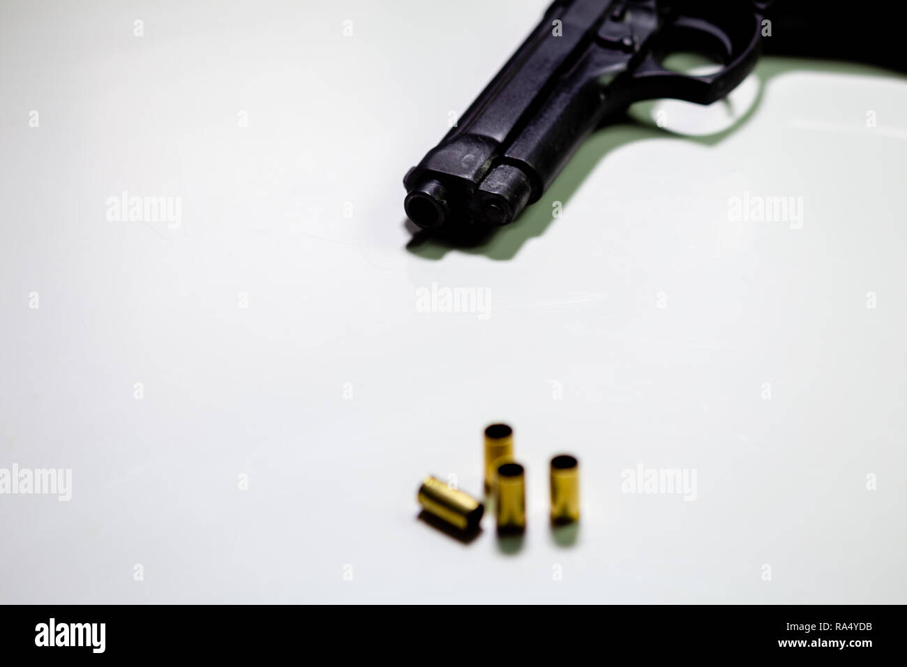Pistol with 9mm shell casings on white table Stock Photo - Alamy