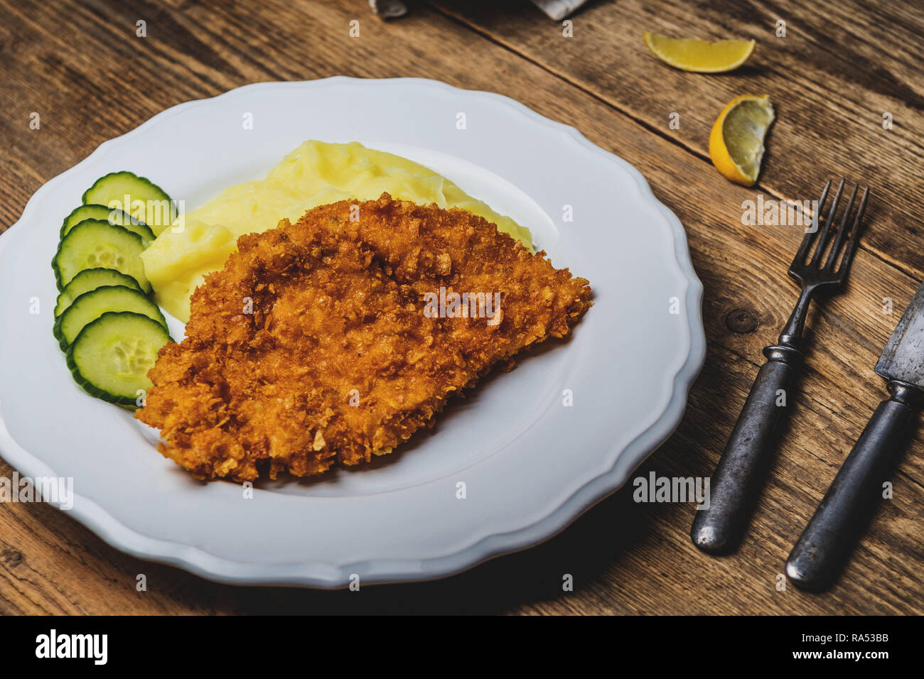 Chicken fried schnitzel with mashed potatoes and lemon on wood table ...