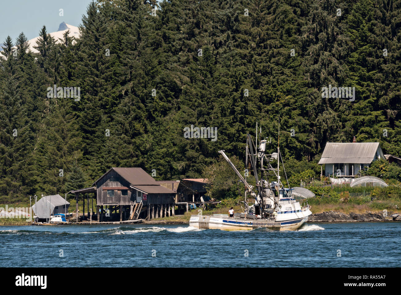 A fishing boat heads down the Wrangell Narrows past the tiny village of ...