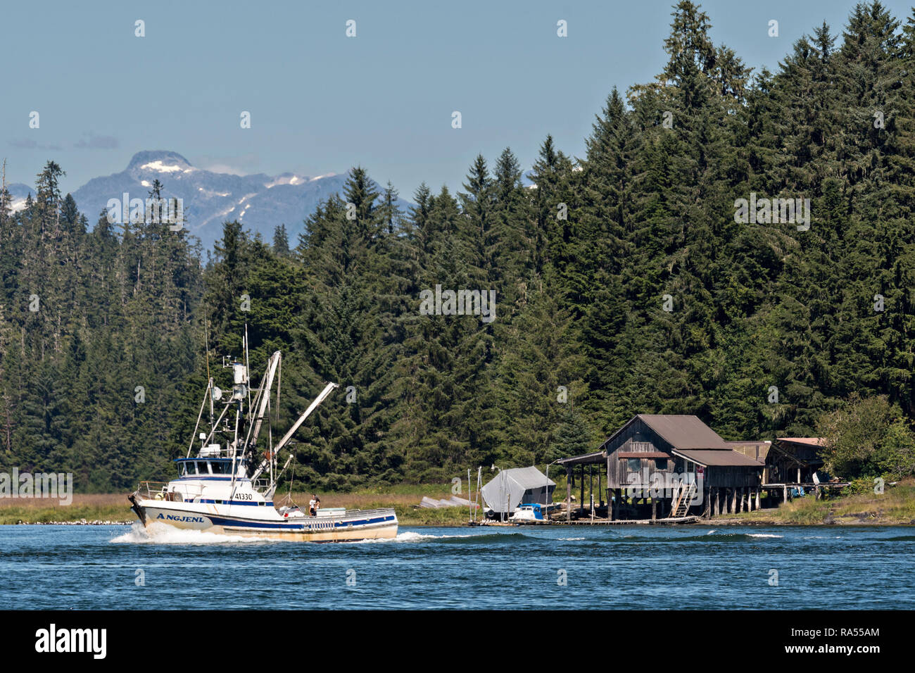 A fishing boat heads down the Wrangell Narrows past the tiny village of ...