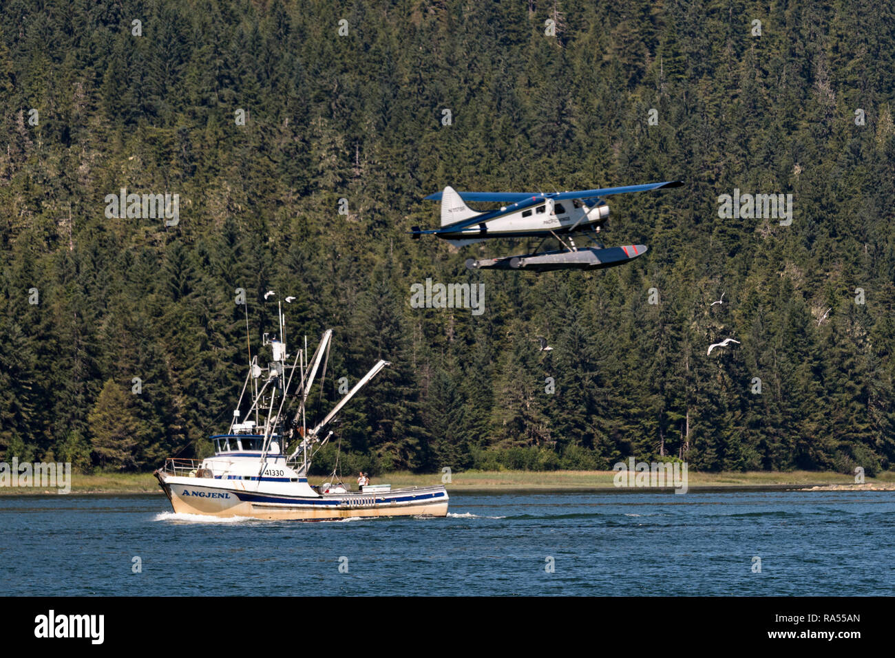 A fishing boat heads down the Wrangell Narrows as a float plane takes ...