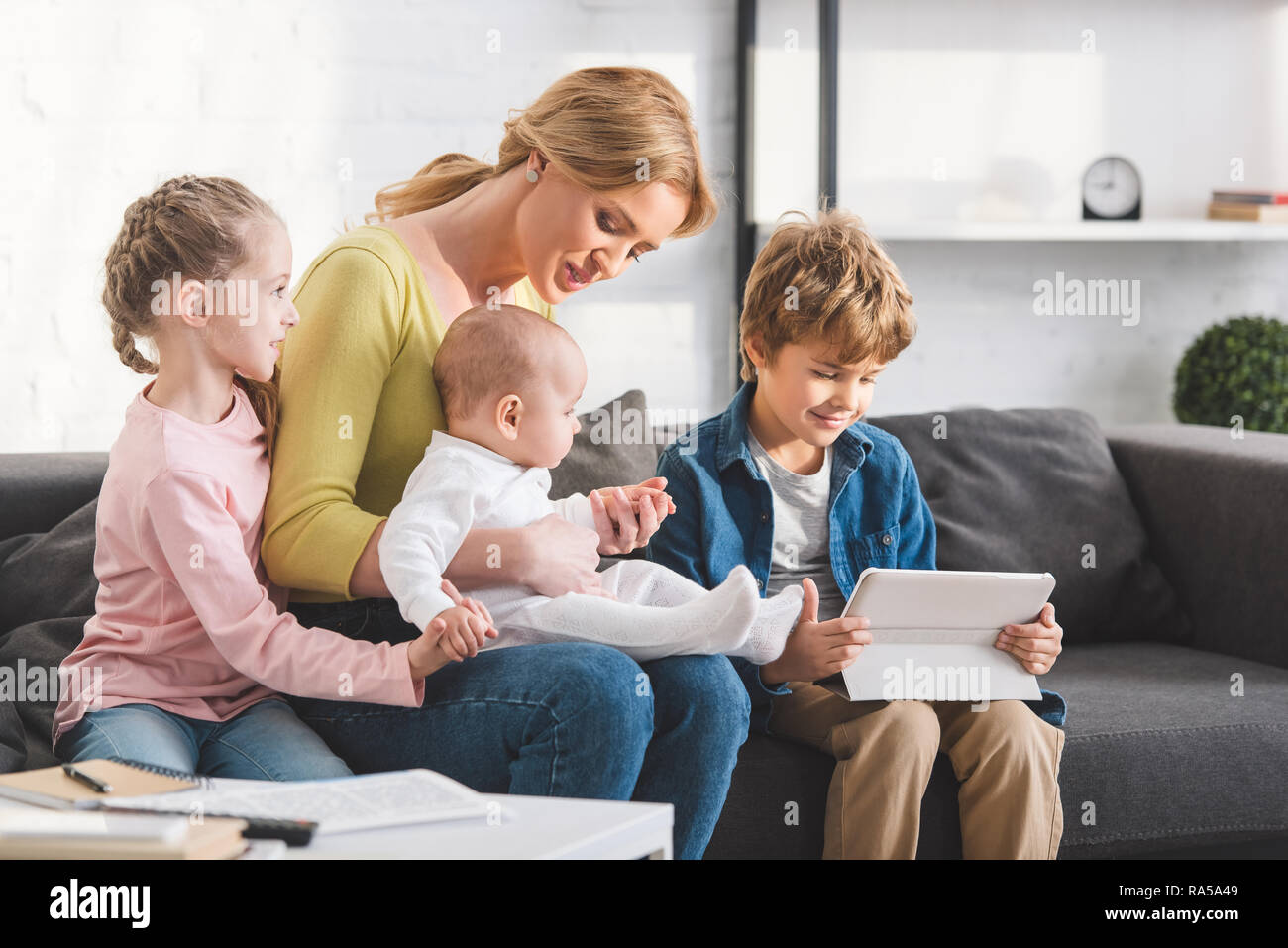 beautiful happy mother with three adorable children sitting together on ...