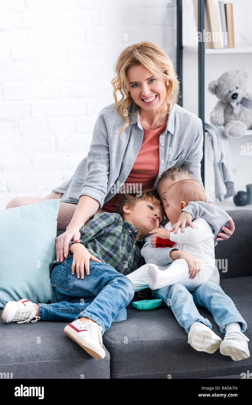 beautiful happy mother smiling at camera while three adorable kids ...