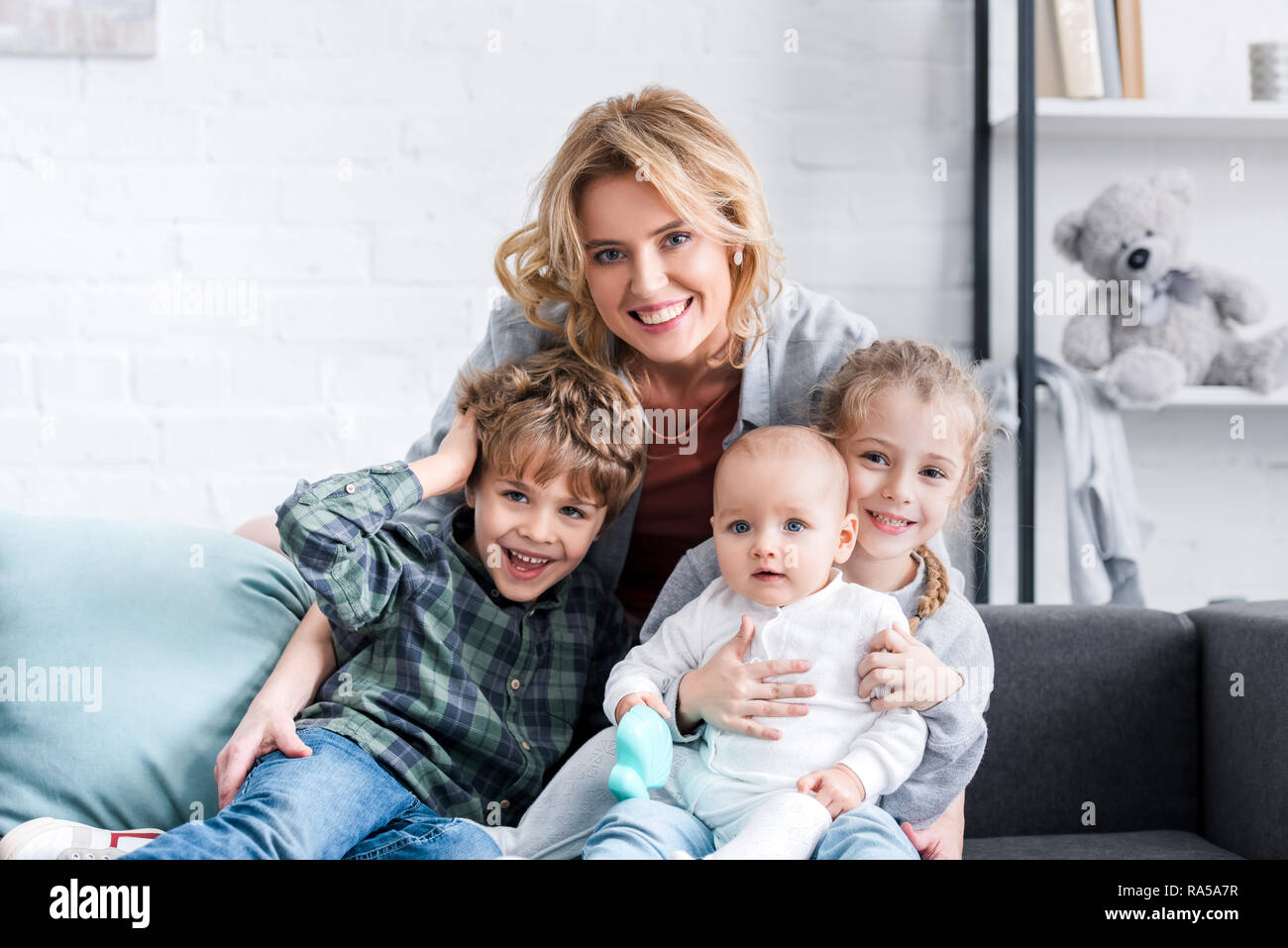 beautiful happy mother with three adorable children smiling at camera ...