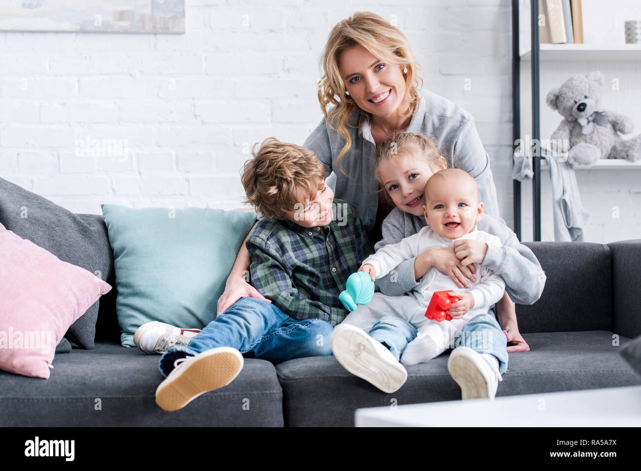 beautiful happy mother with three adorable kids smiling at camera Stock ...