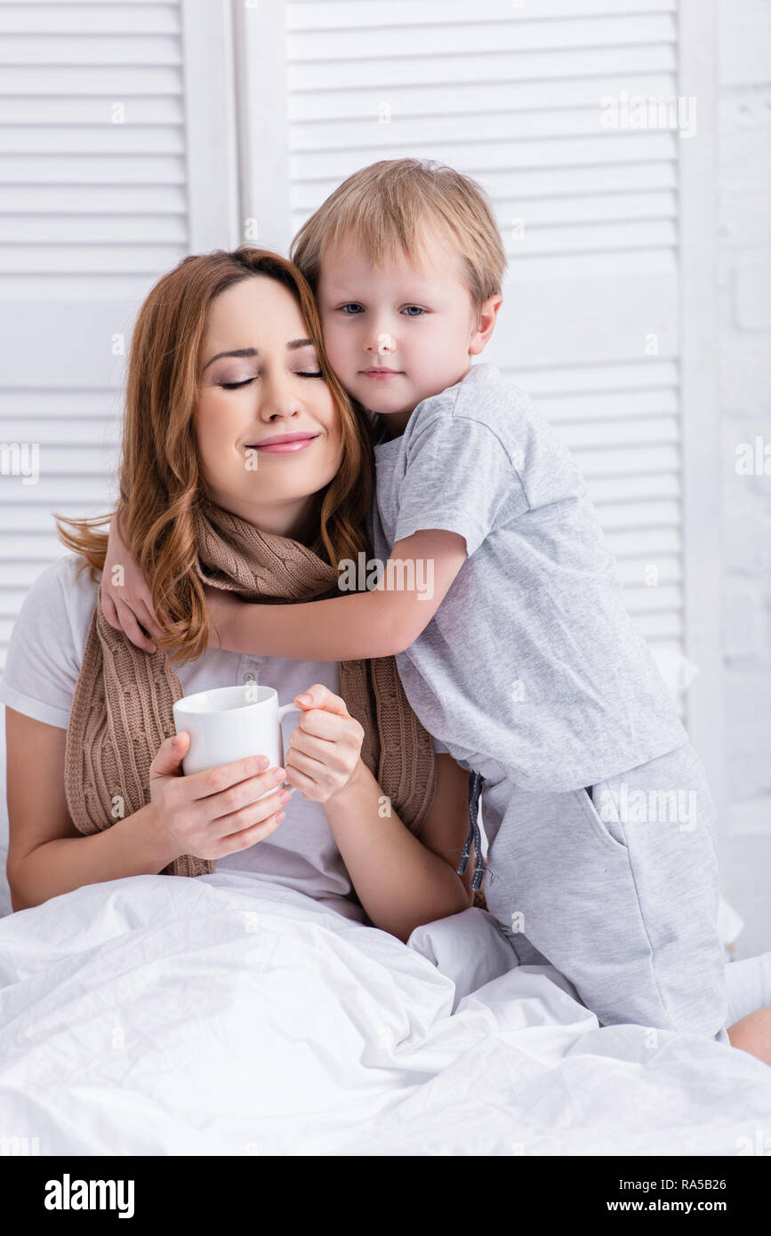 adorable son hugging sick mother in bedroom Stock Photo - Alamy