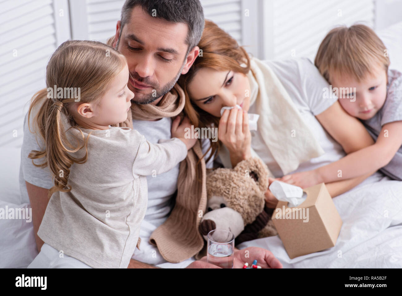 adorable sister and brother hugging sick parents in bedroom Stock Photo ...