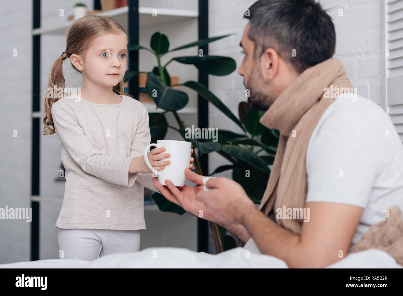 adorable daughter giving cup of tea to sick dad in bedroom Stock Photo ...