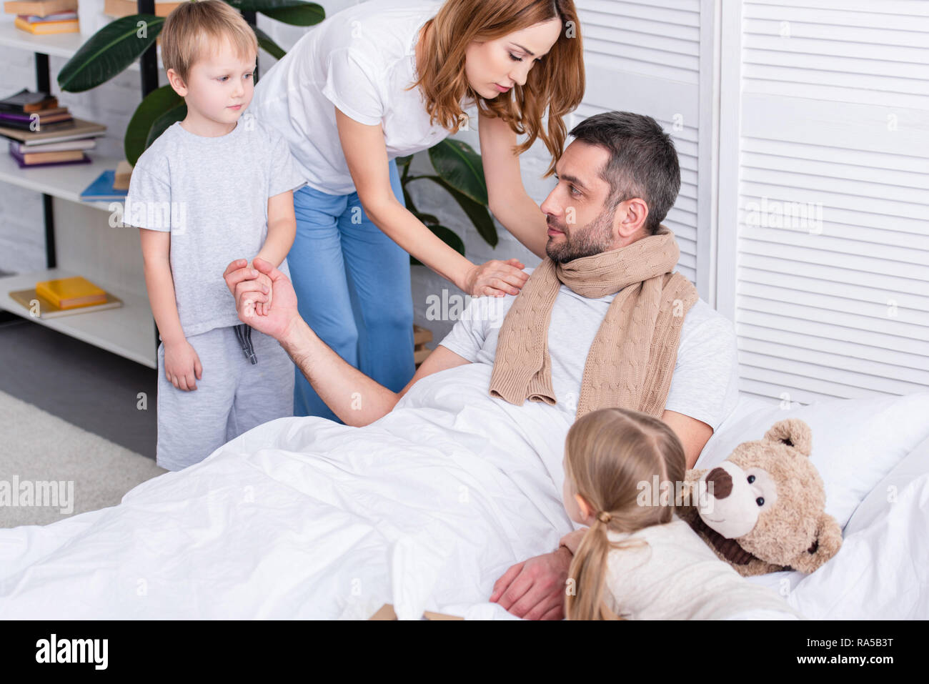 wife, son and daughter taking care of sick father in bedroom Stock ...