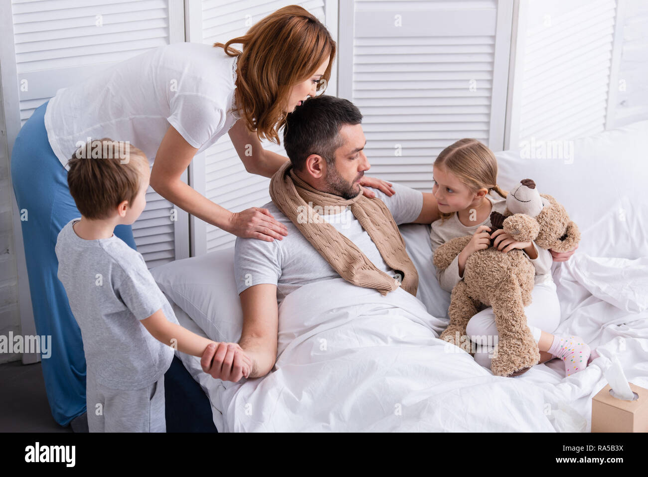 high angle view of wife and children taking care of sick father in ...