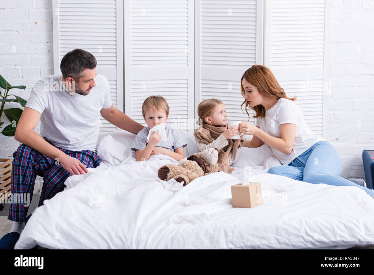 parents taking care of sick daughter and son in bedroom Stock Photo - Alamy