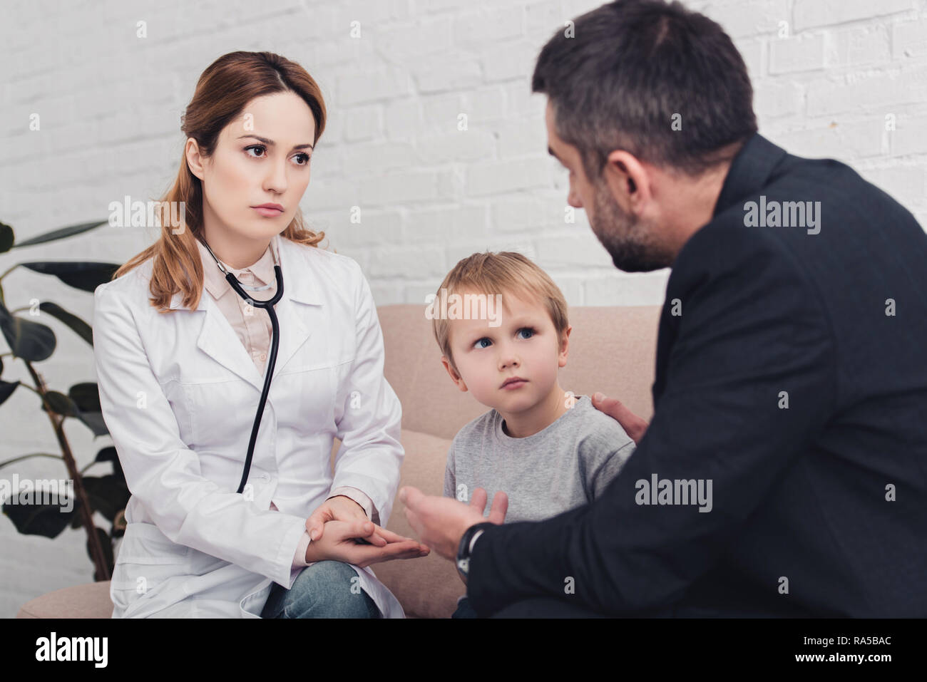 pediatrist and man talking about sick boy in living room Stock Photo ...