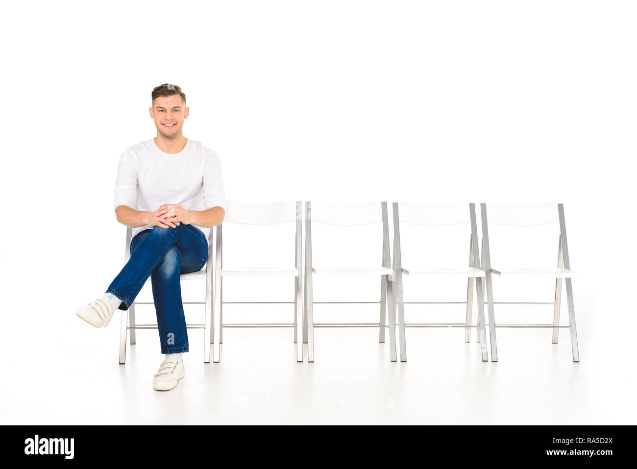 handsome young man sitting with crossed legs isolated on white Stock ...